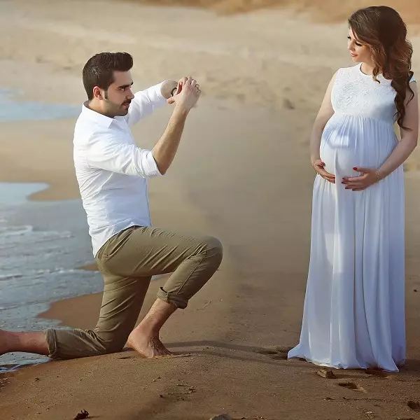 The groom takes pictures of a pregnant wife